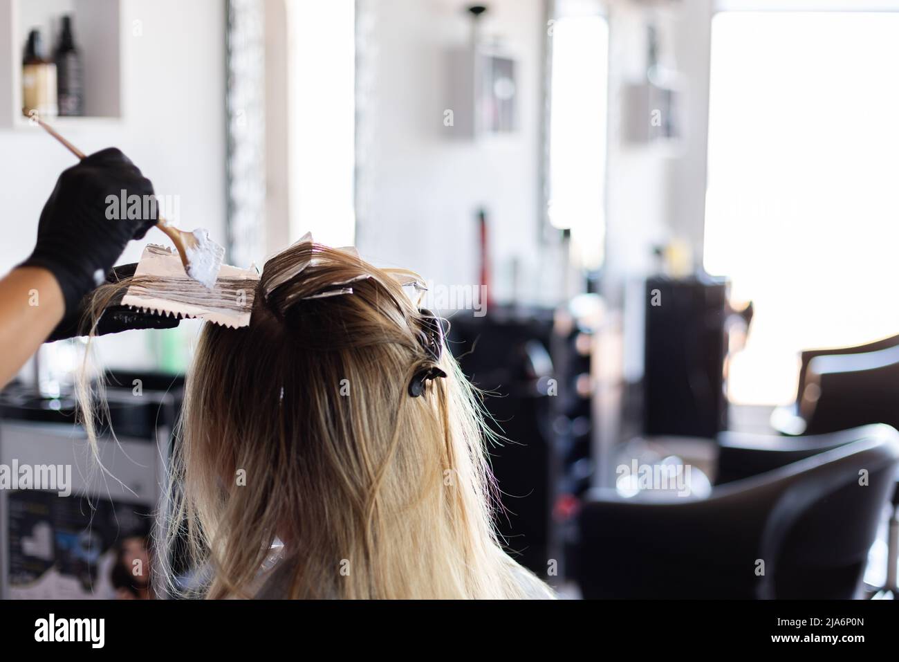Putting hair dye on the strand of hair. Colouring hair at beauty salon ...