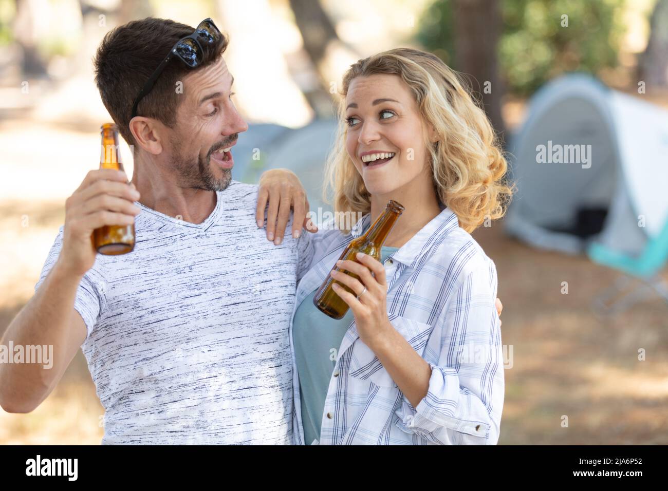 happy couple clinking beer bottles at campsite tent Stock Photo - Alamy