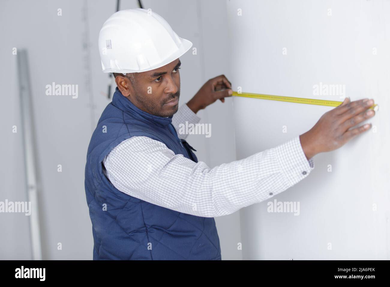 male builder measuring interior wall Stock Photo - Alamy