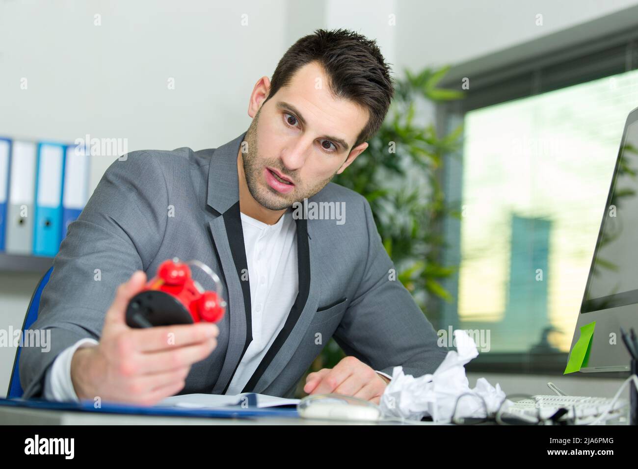 office worker looking at the alarm clock Stock Photo - Alamy