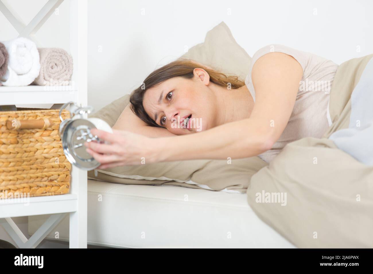 woman with alarm expression looking at alarm clock Stock Photo - Alamy