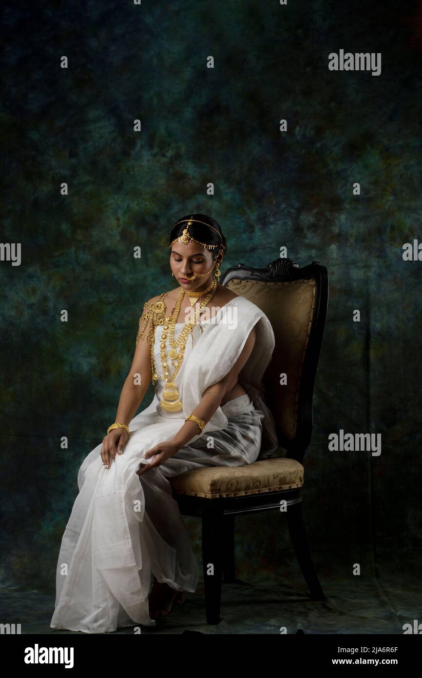 indian woman in a traditional white saree and gold jewellry to ...