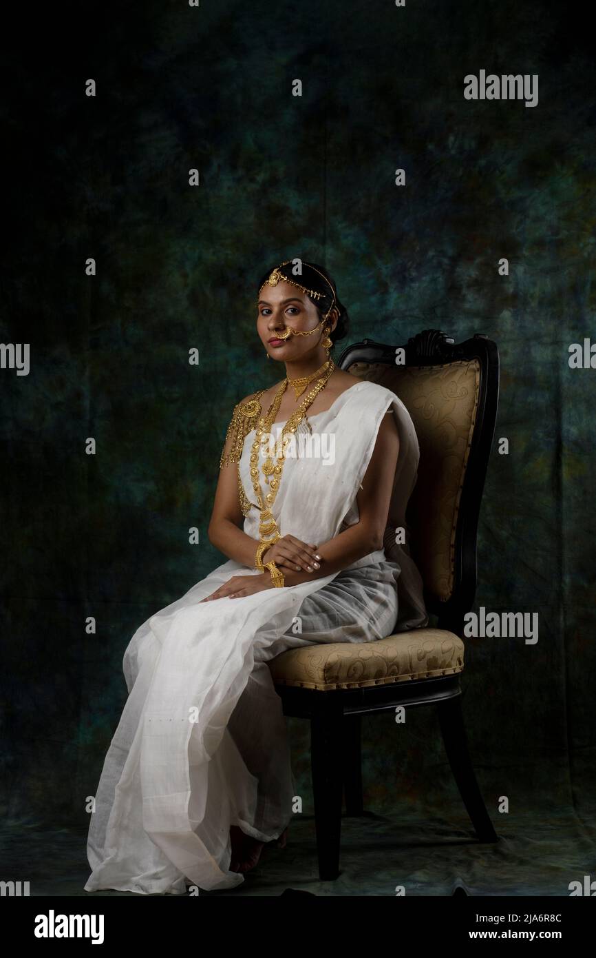indian woman in a traditional white saree and gold jewellry to ...