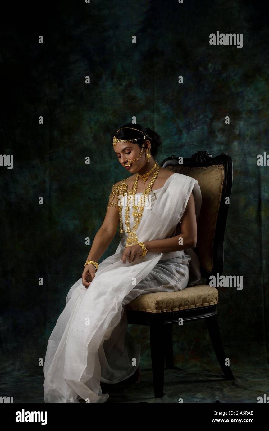 indian woman in a traditional white saree and gold jewellry to ...