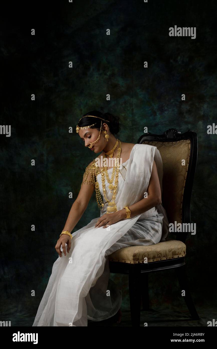 indian woman in a traditional white saree and gold jewellry to ...