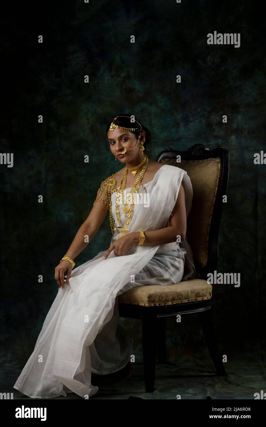 Indian female model wearing a white saree and gold jewellry sporting a ...
