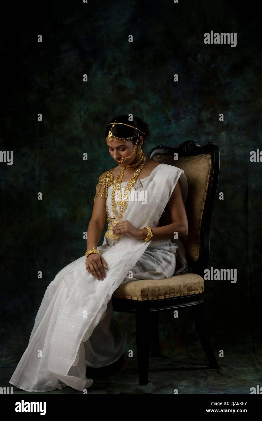 indian woman in a traditional white saree and gold jewellry to ...