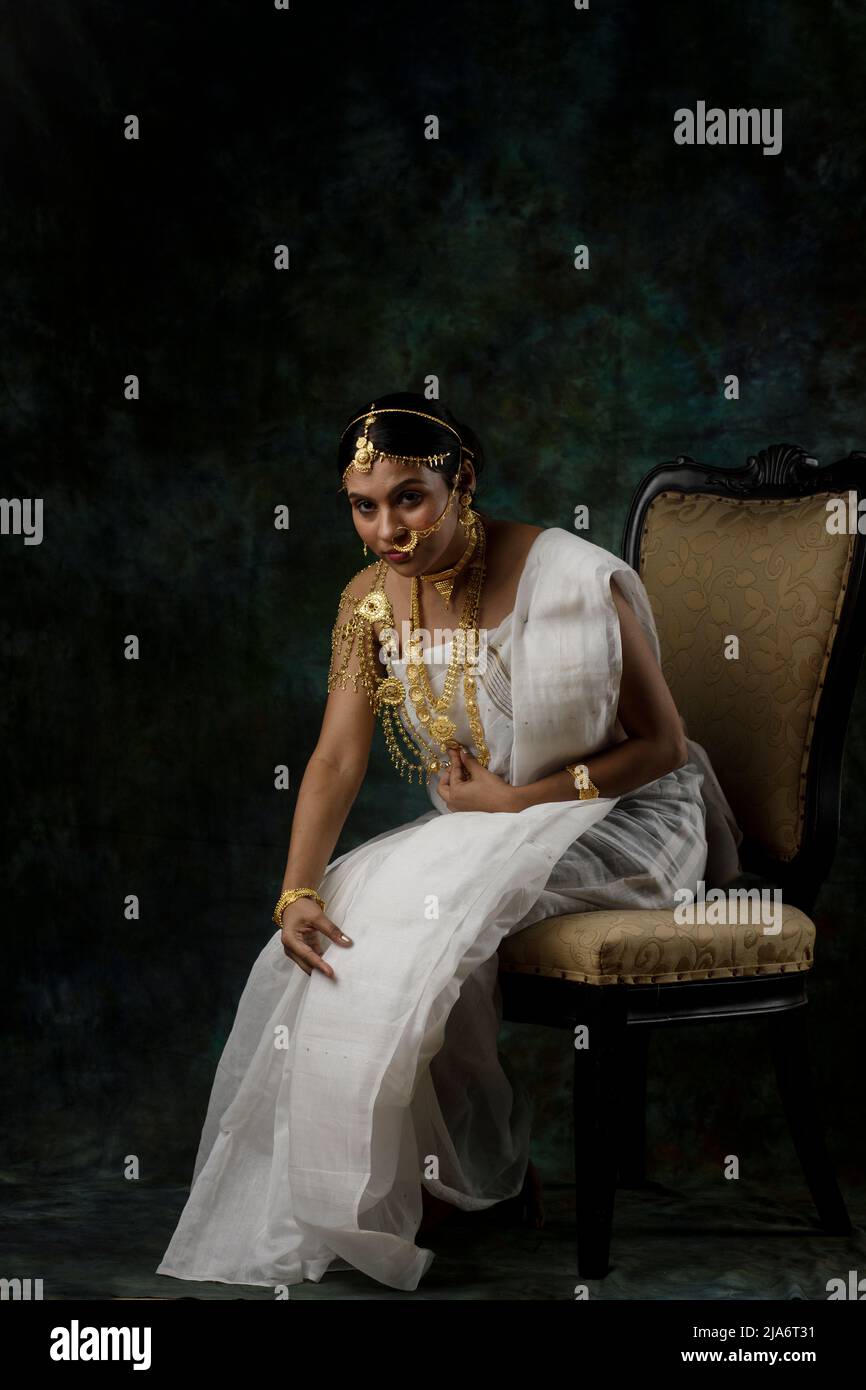 indian woman in a traditional white saree and gold jewellry to ...
