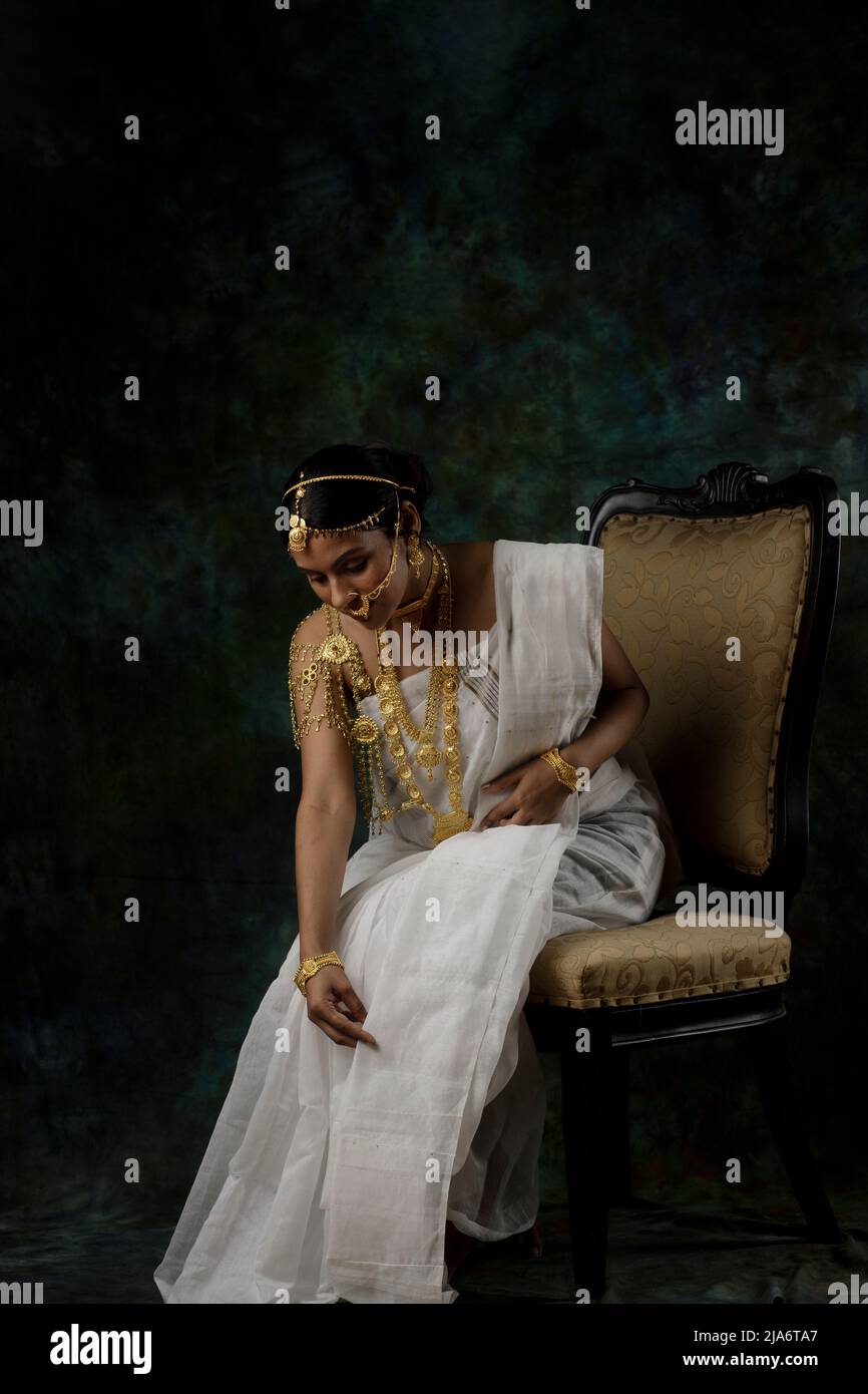 indian woman in a traditional white saree and gold jewellry to ...