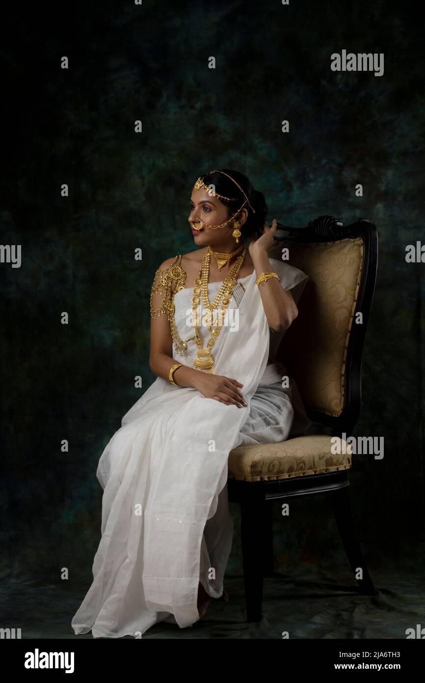 indian woman in a traditional white saree and gold jewellry to ...