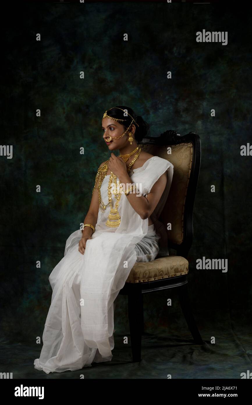 indian woman in a traditional white saree and gold jewellry to ...