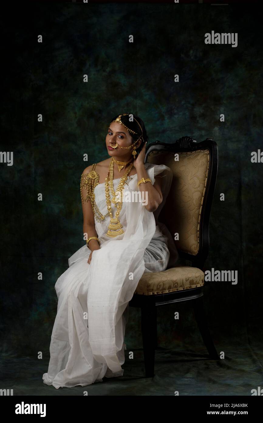 indian woman in a traditional white saree and gold jewellry to ...