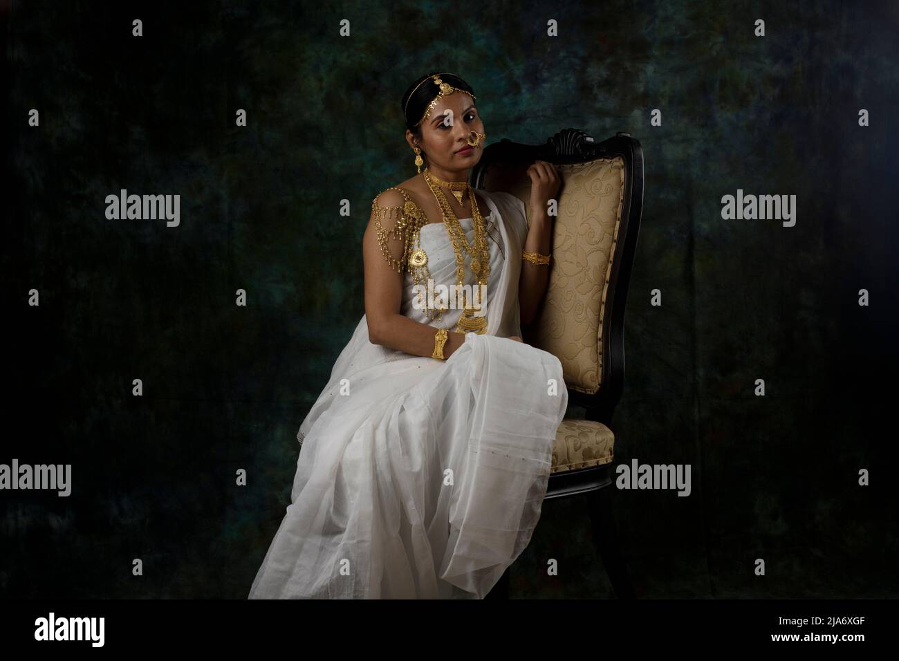indian woman in a traditional white saree and gold jewellry to represent the binodini look of ...