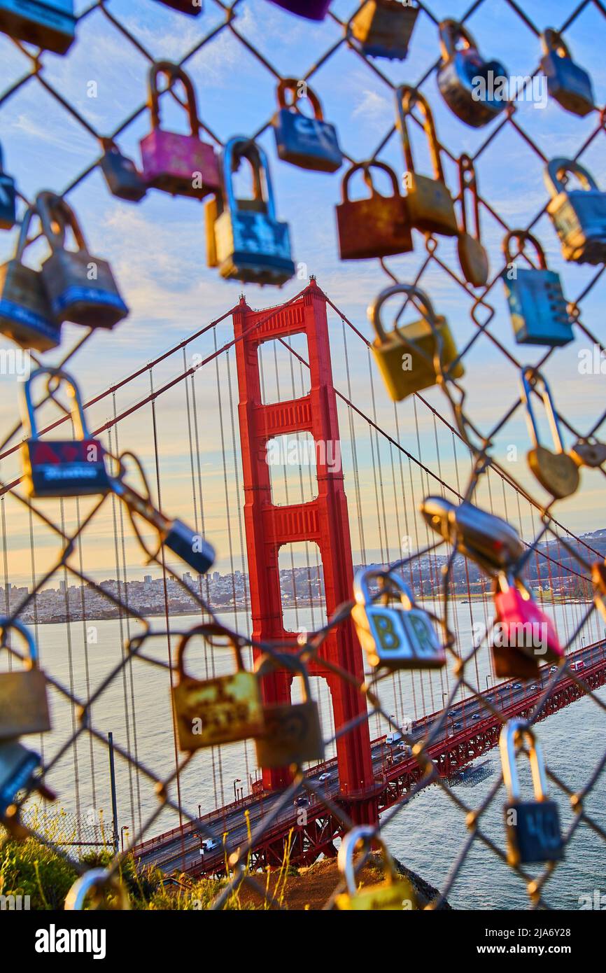 Golden Gate Bridge through opening in chain link fence covered in locks ...
