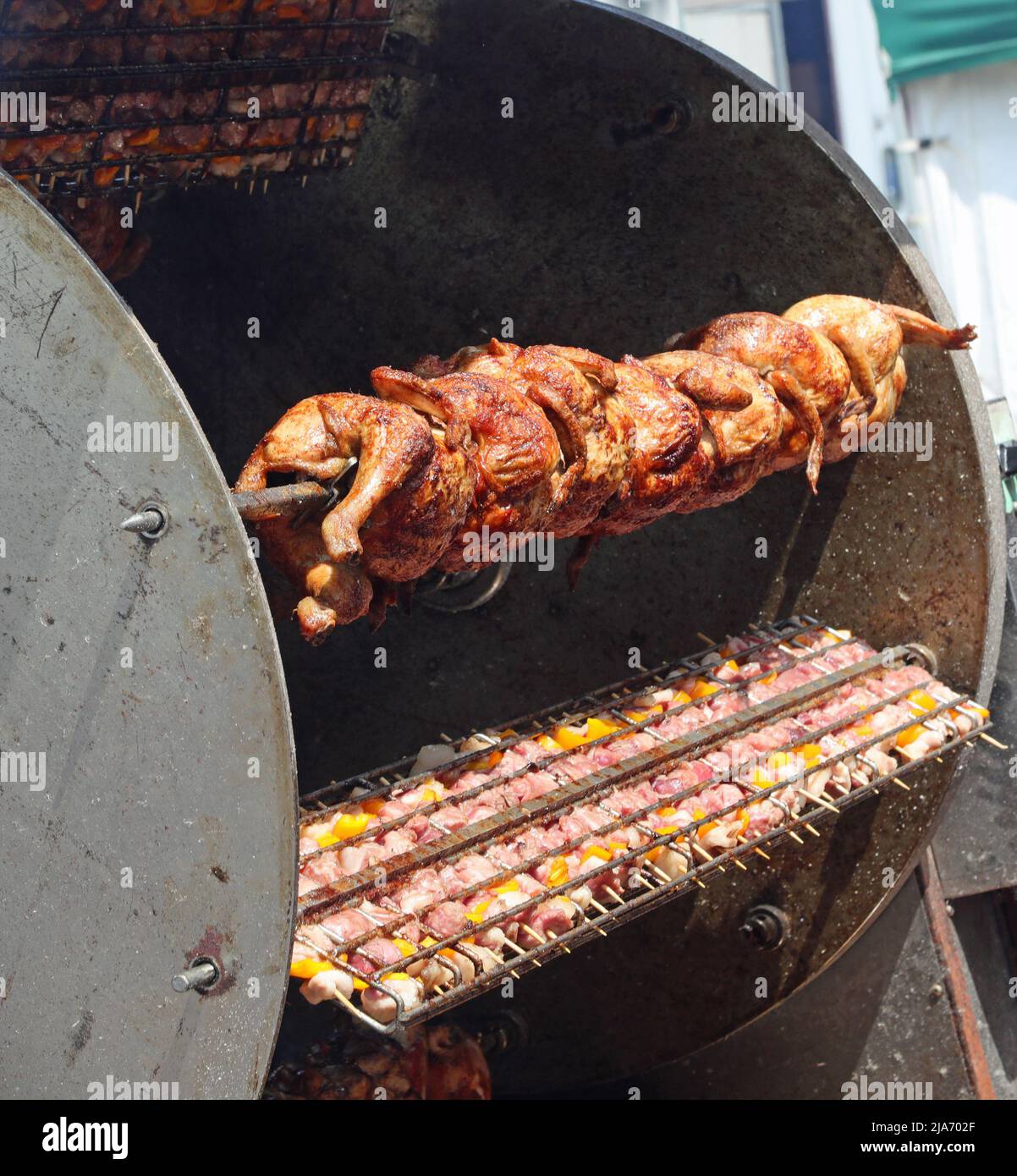 large industrial rotisserie with spit-roasted chickens and skewers of ...