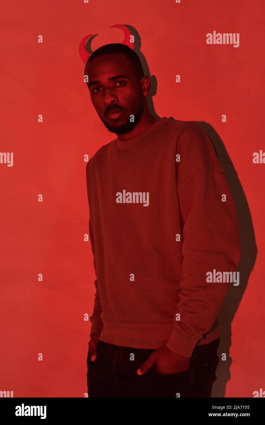 Portrait of serious young African-American man in devil headband ...