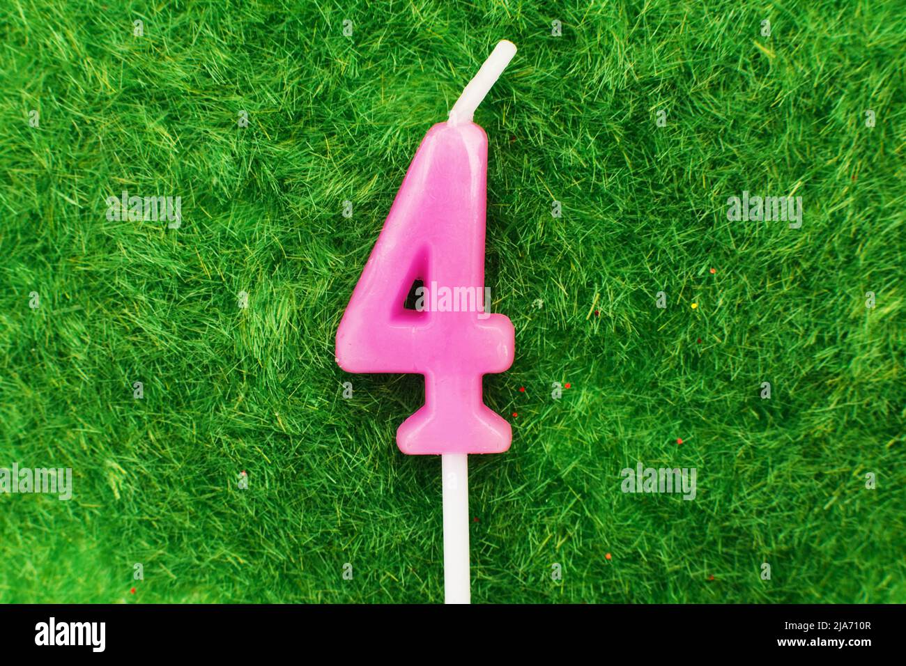 candle in the form of number four on the green grass background, a ...