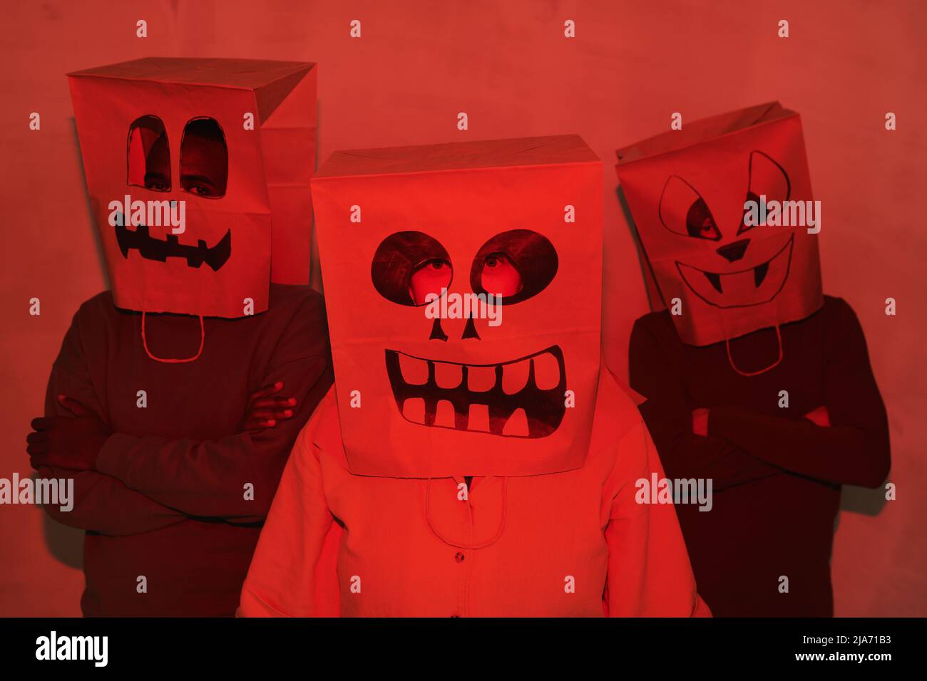 Group of people in funny paper bag masks standing together in red dark ...