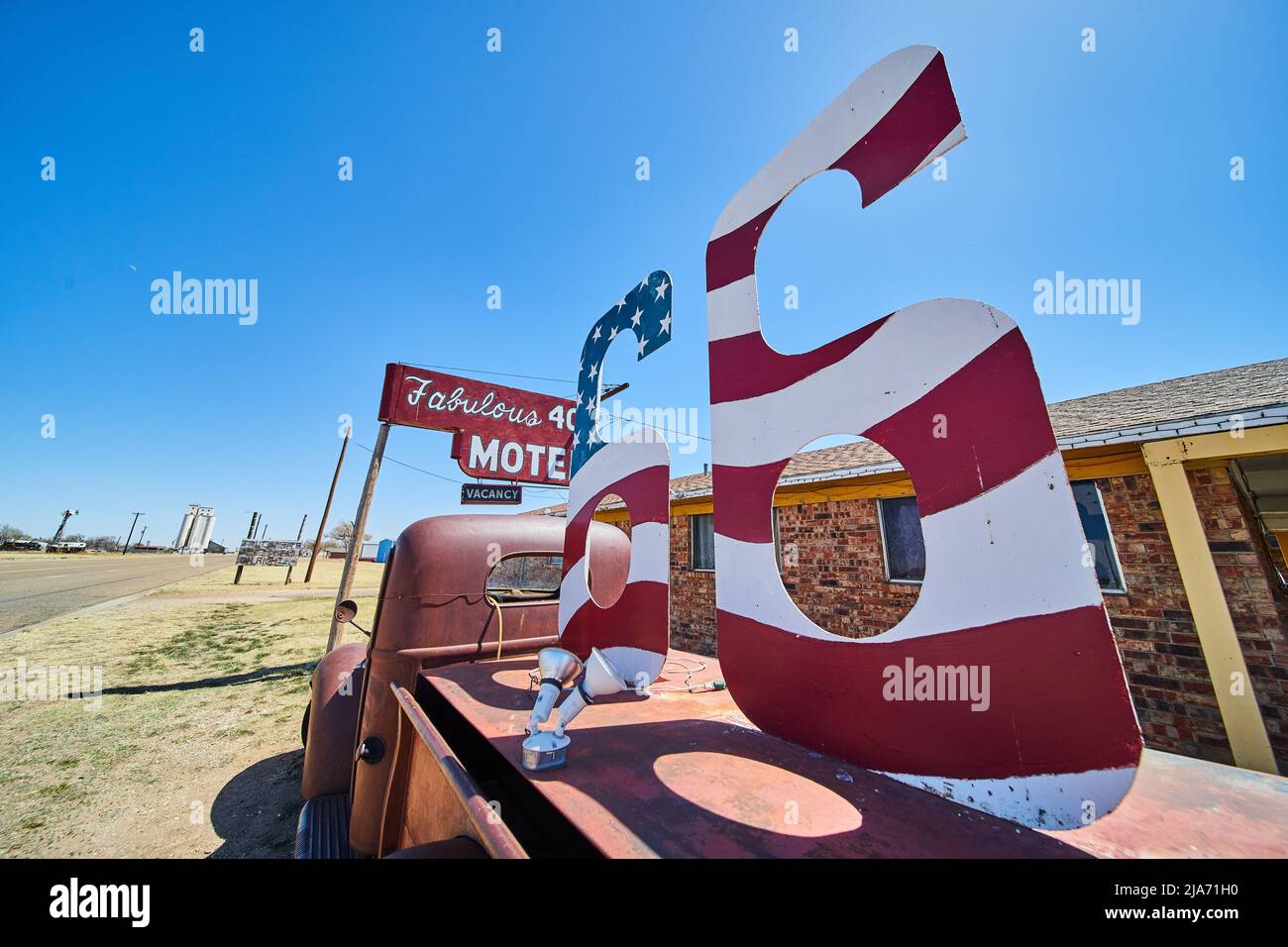 Iconic Route 66 sign with American Flag pattern on old truck by motel ...