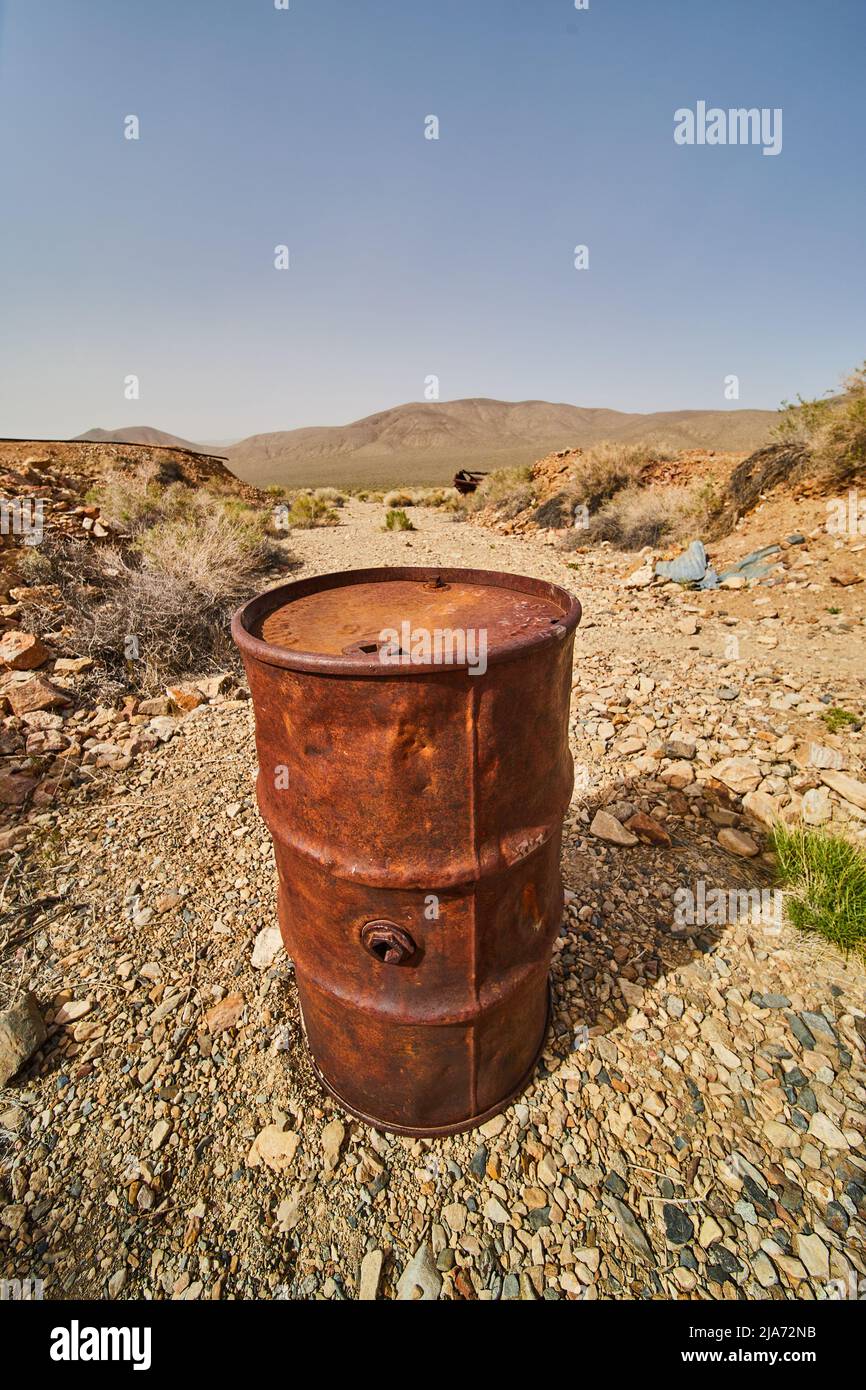 Desert with detail of large orange rusted mining barrel Stock Photo - Alamy