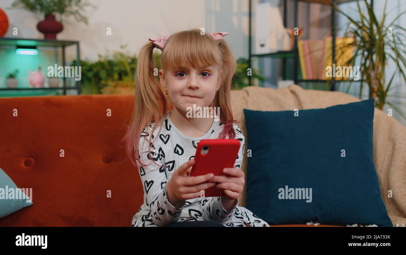 Excited amazed winner kid girl use mobile phone say wow yes raising ...