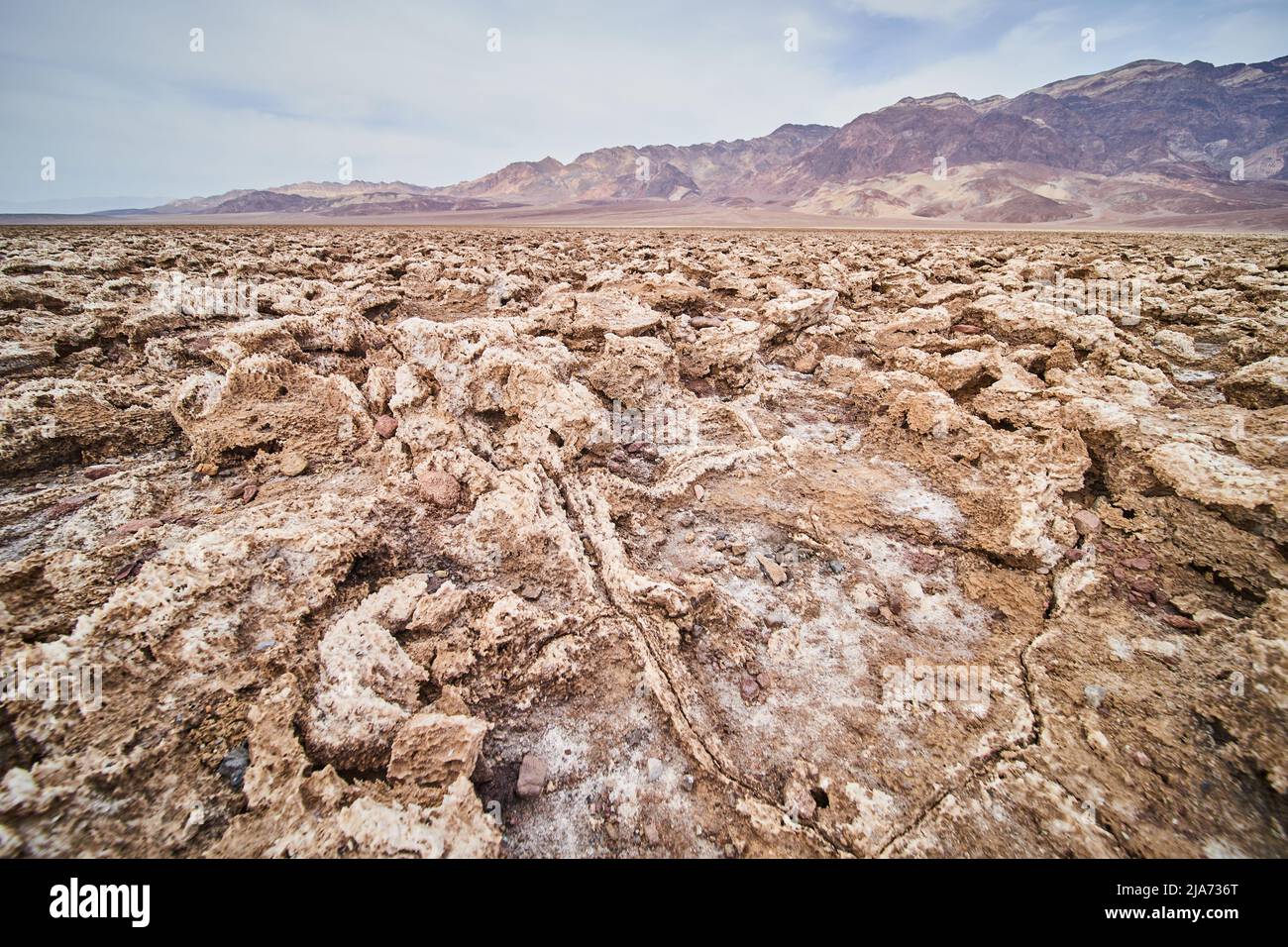 Cracks in ground of salt flats with eroded salt formations in Death ...