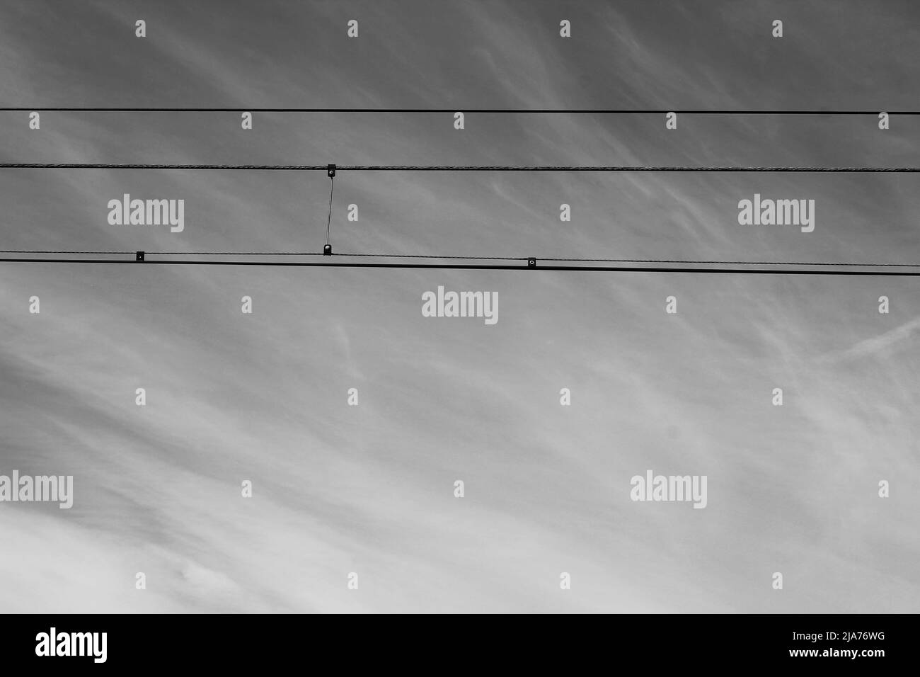 Electrical power lines crossing overhead against the sky in black and ...