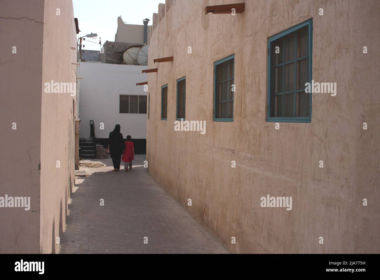 A Bahraini woman and child walking along a narrow alley on the Pearl ...