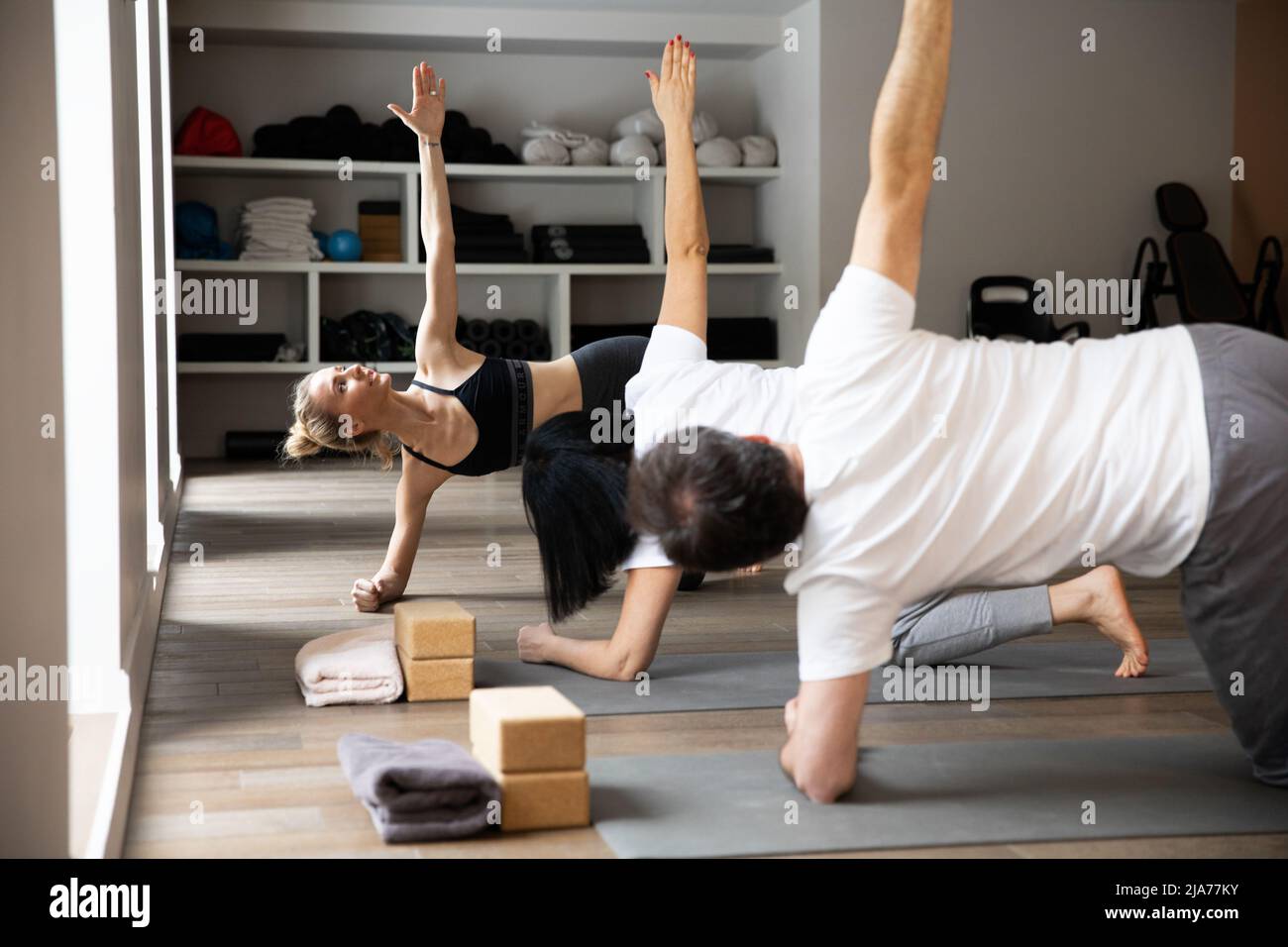 A female yoga and pilates trainer conducts a group class in a practice ...