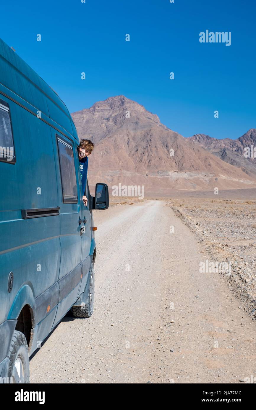 boy looking out the window of a campervan with a dusty road ahead Stock ...