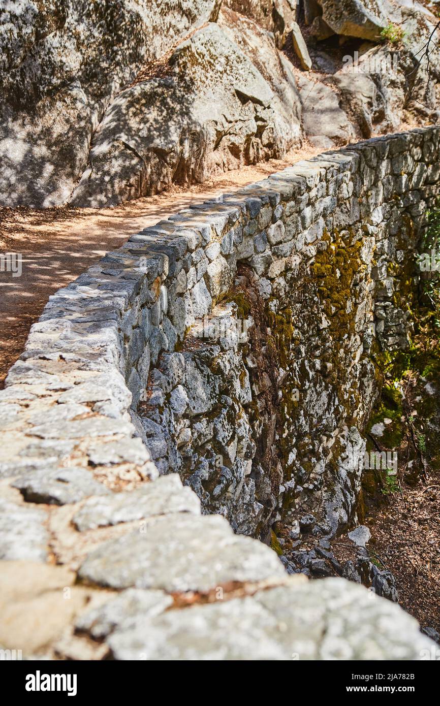Hiking path featuring giant stone wall along cliffs Stock Photo - Alamy