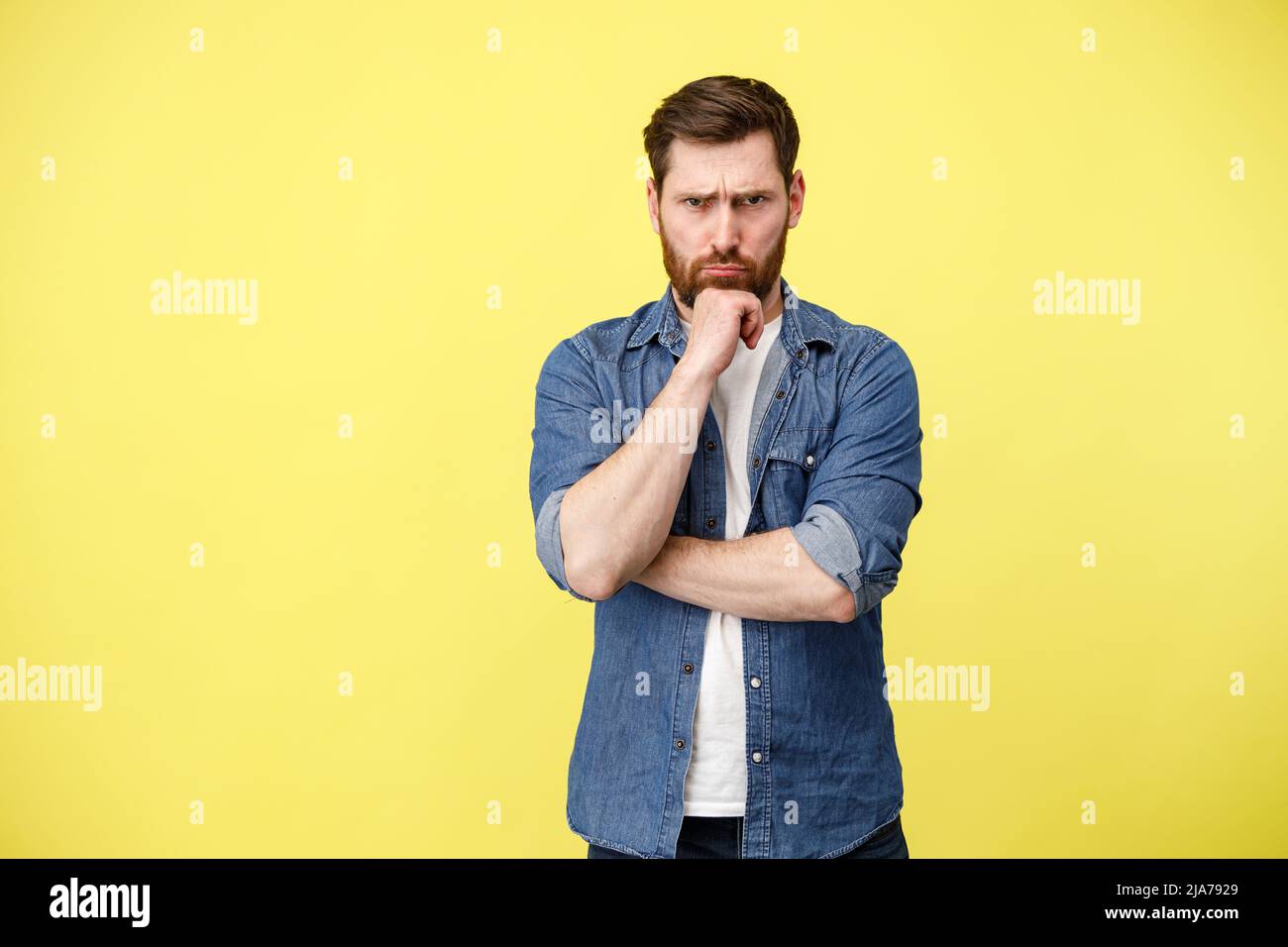 Serious man houghtfully hold hand near beard in yellow background Stock ...
