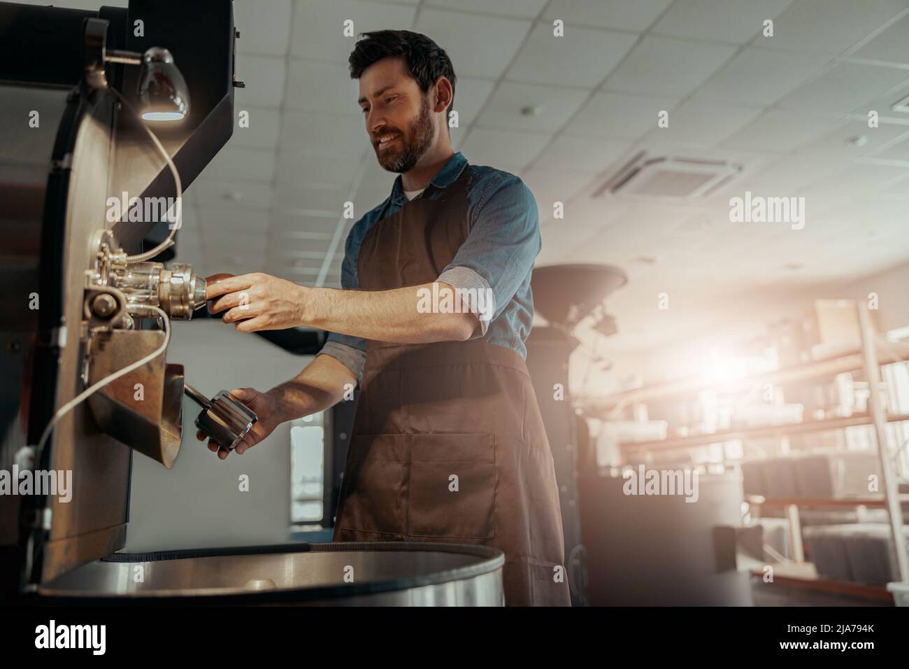 Business owner operating a modern coffee bean roasting machine Stock ...