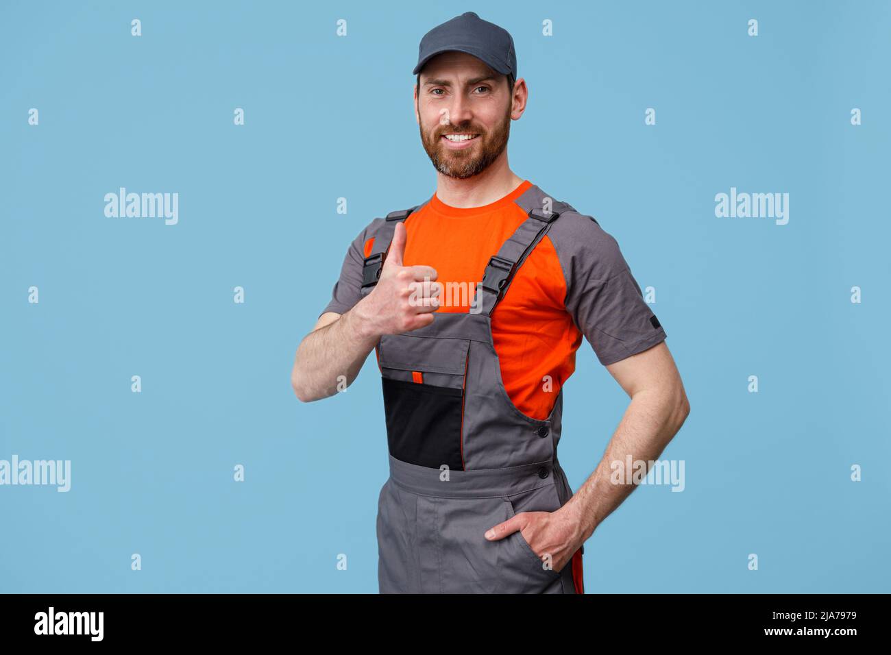 Portrait of smiling workerman In uniform showing thumbs up and looking ...