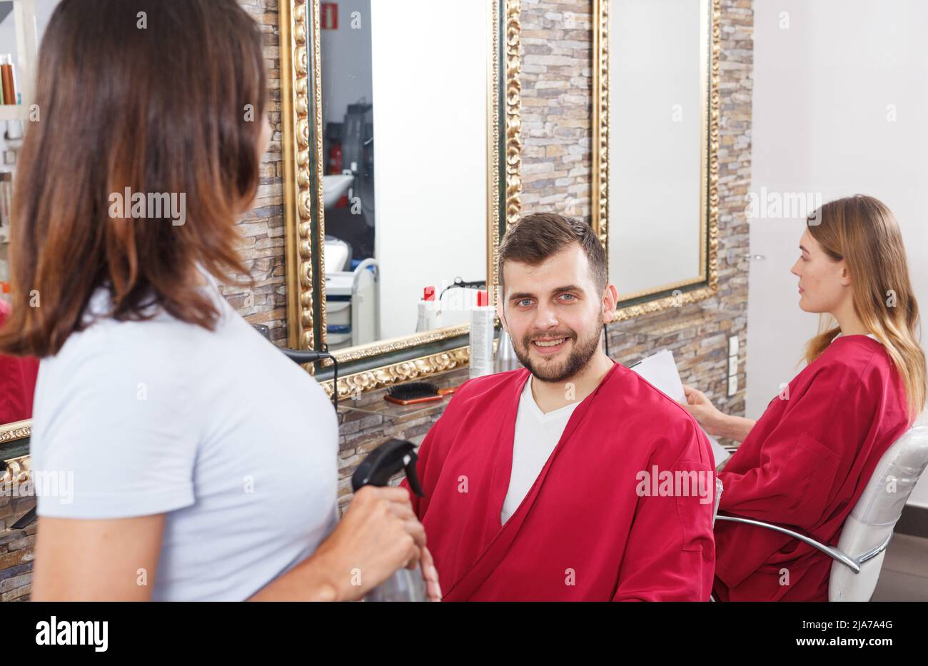 Positive man client sitting at chair in hairdressing salon Stock Photo ...