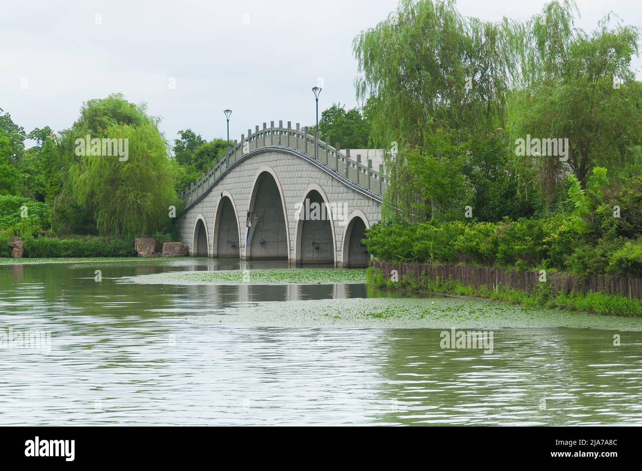 an arched bridge over a pond on an overcast day within the jingshan ...