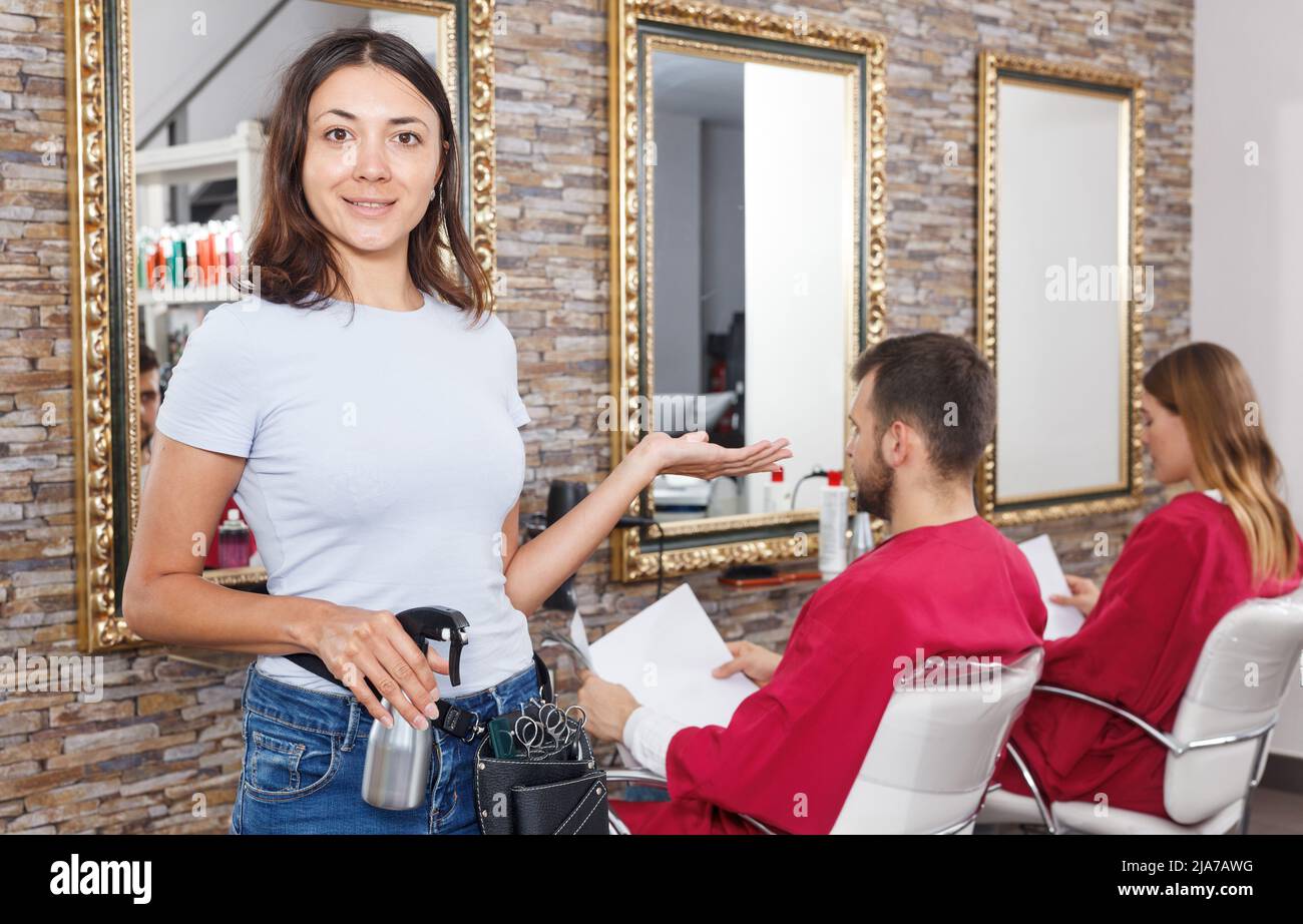 Young female hairstylist standing in salon, clients on background Stock ...