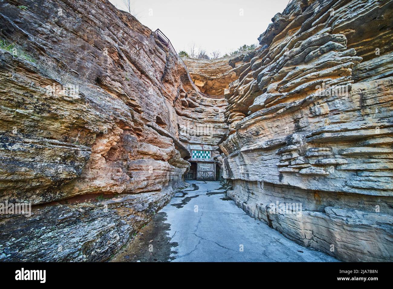 Eerie canyon cliffs with paved path leading into mysterious cave Stock ...