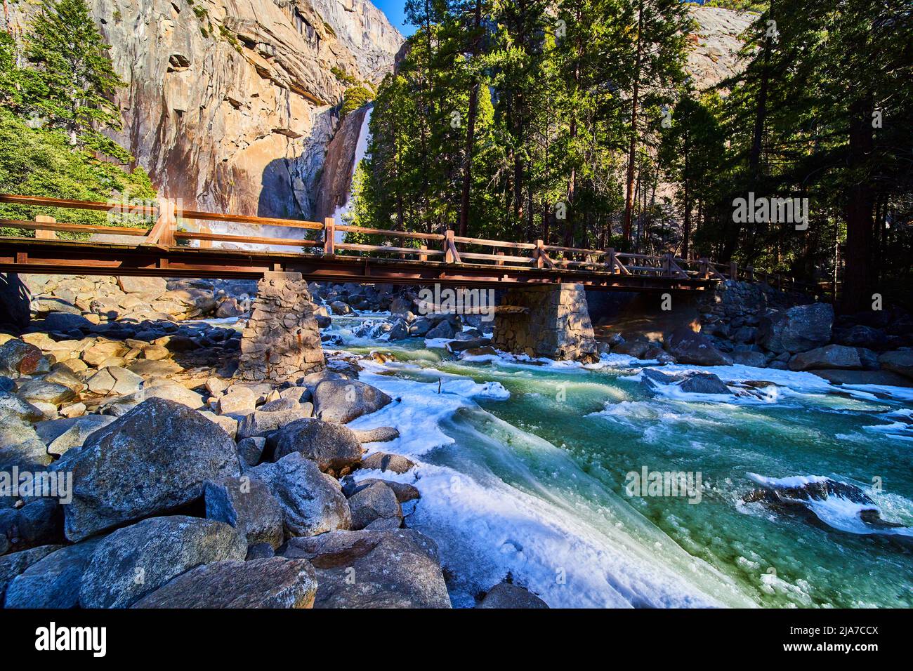 Bridge crossing over dangerous slushy cold river with Yosemite Lower ...