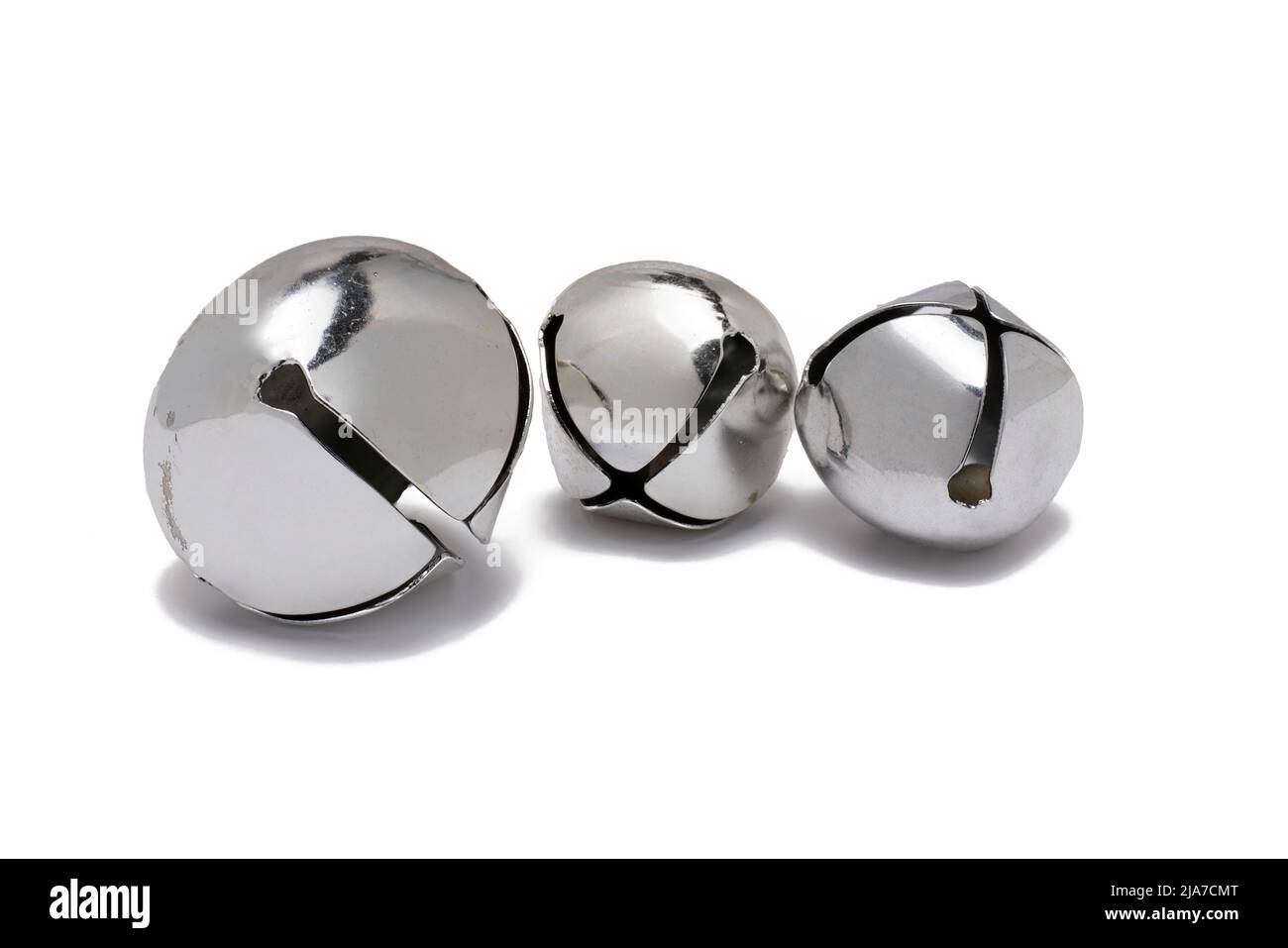 Close up three different size shiny silver metal bells on white ...
