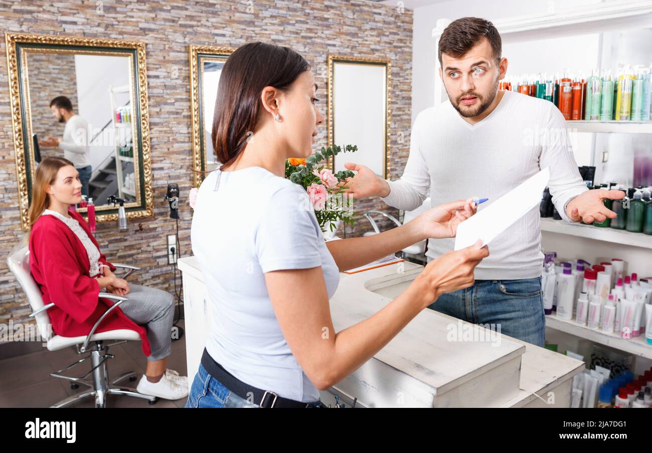 Woman client discussing with man assistant about services at beauty ...