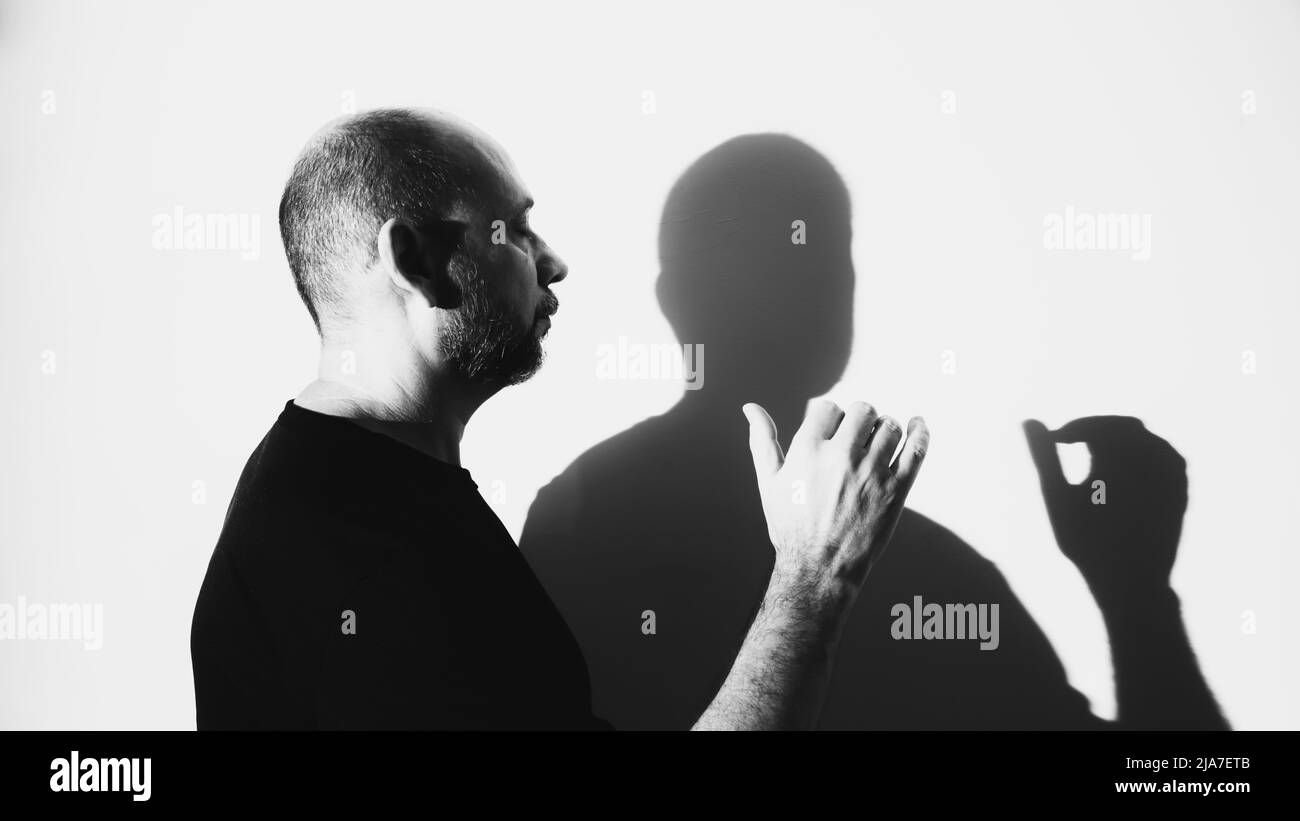 Portrait of a man and his shadow against white wall background ...