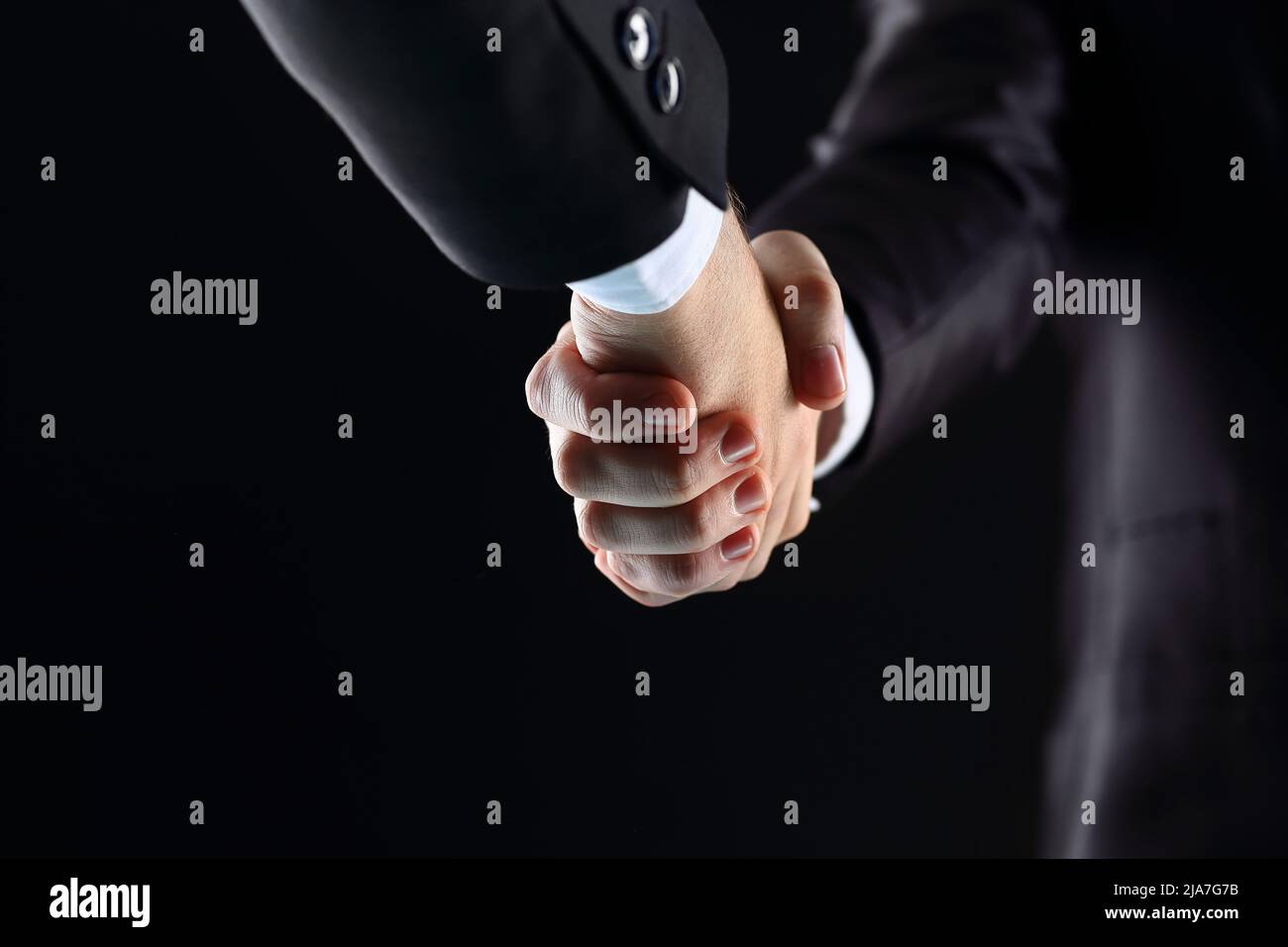 Handshake - Hand holding on black background Stock Photo - Alamy