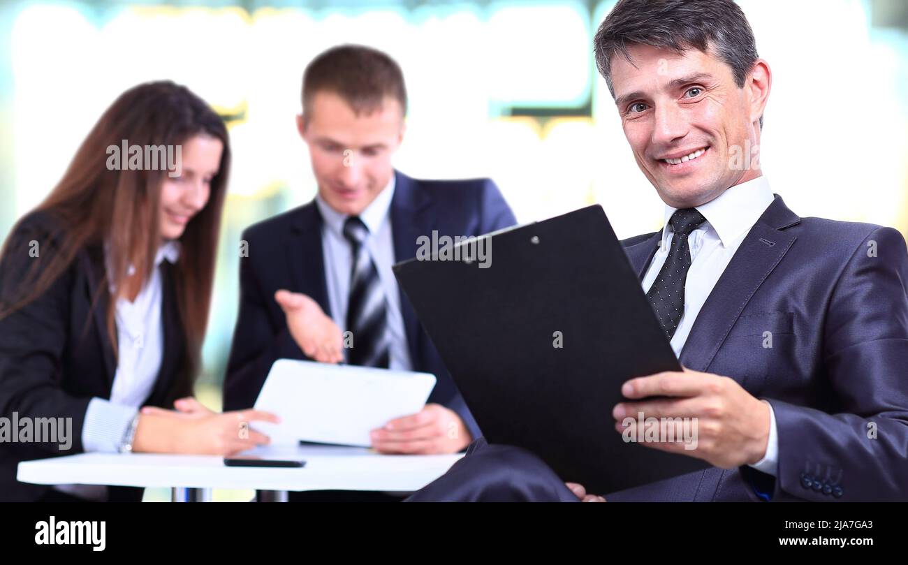 Successful business man standing with his staff in background at office ...