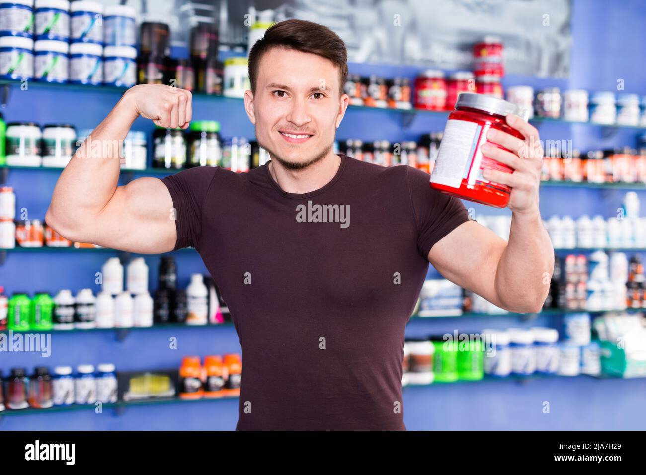 Athletic guy showing muscles while standing in store of sports ...