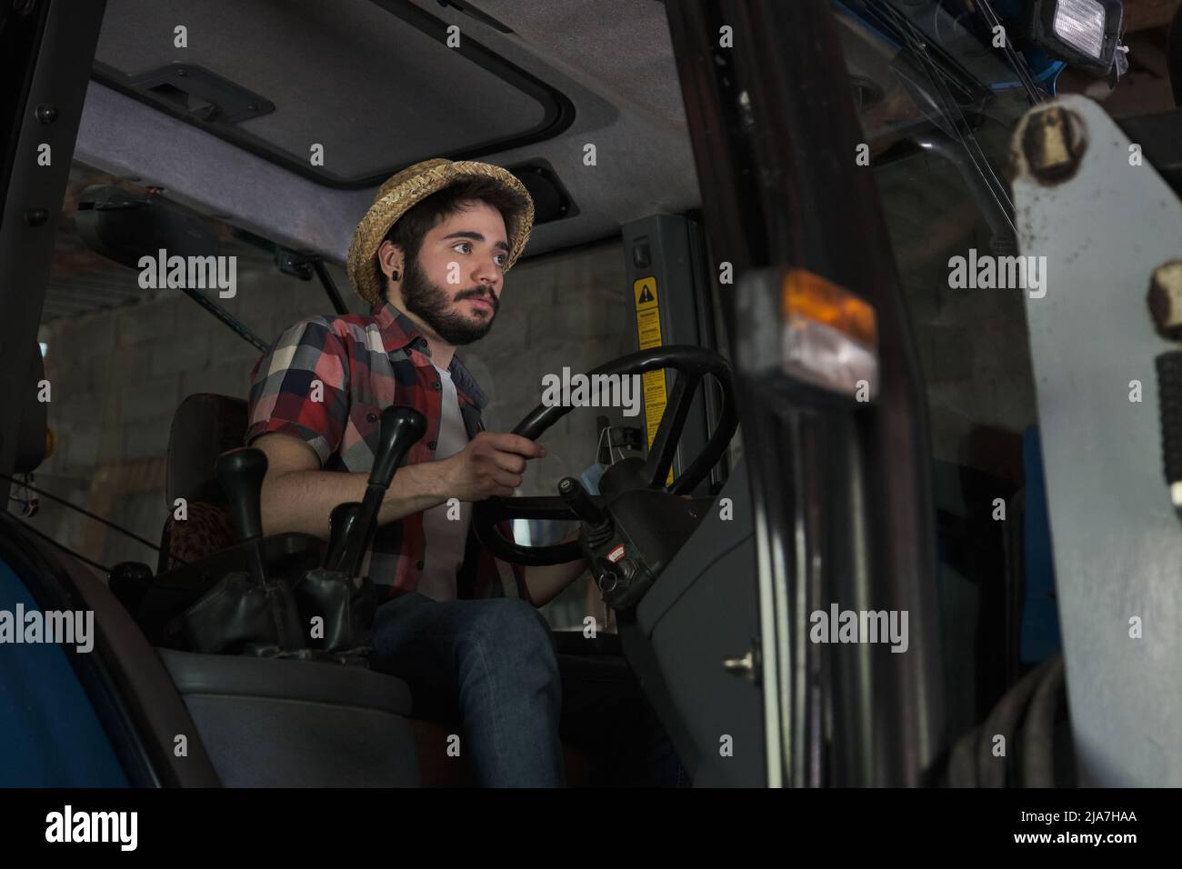 Young farmer driving the tractor out of the barn Stock Photo - Alamy