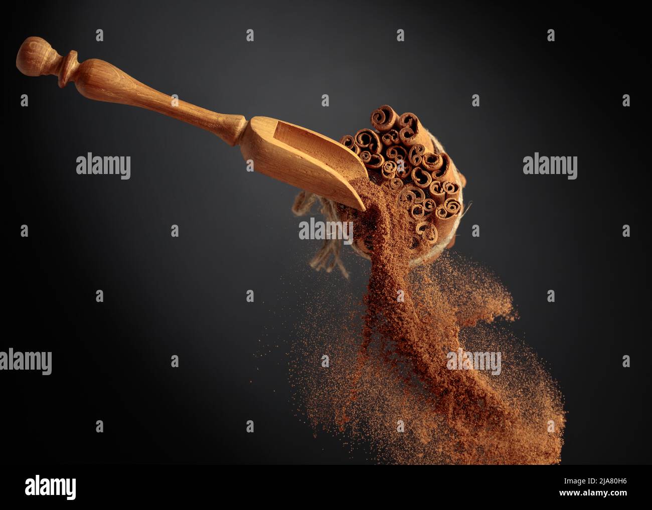 Cinnamon powder is poured out of the wooden spoon. The ground cinnamon ...