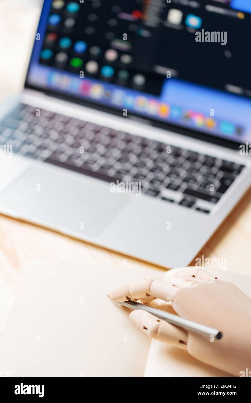 Robotic hand holding a pencil near a notebook. Robot arm works next to ...
