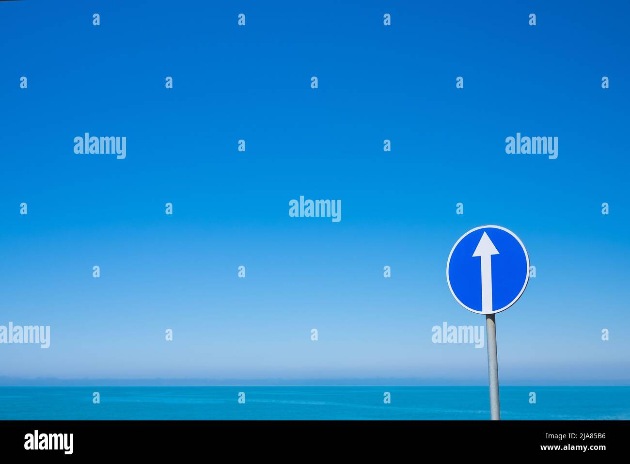 Circle road sign with white arrow on blue sky background. This sign ...