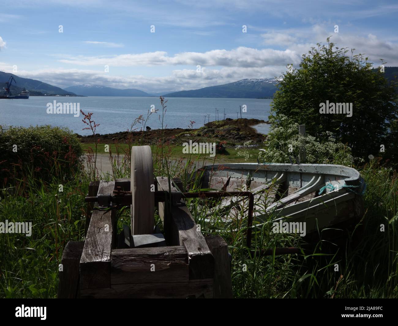An old grindstone and a rowing boat lie deep in the grass at the far ...